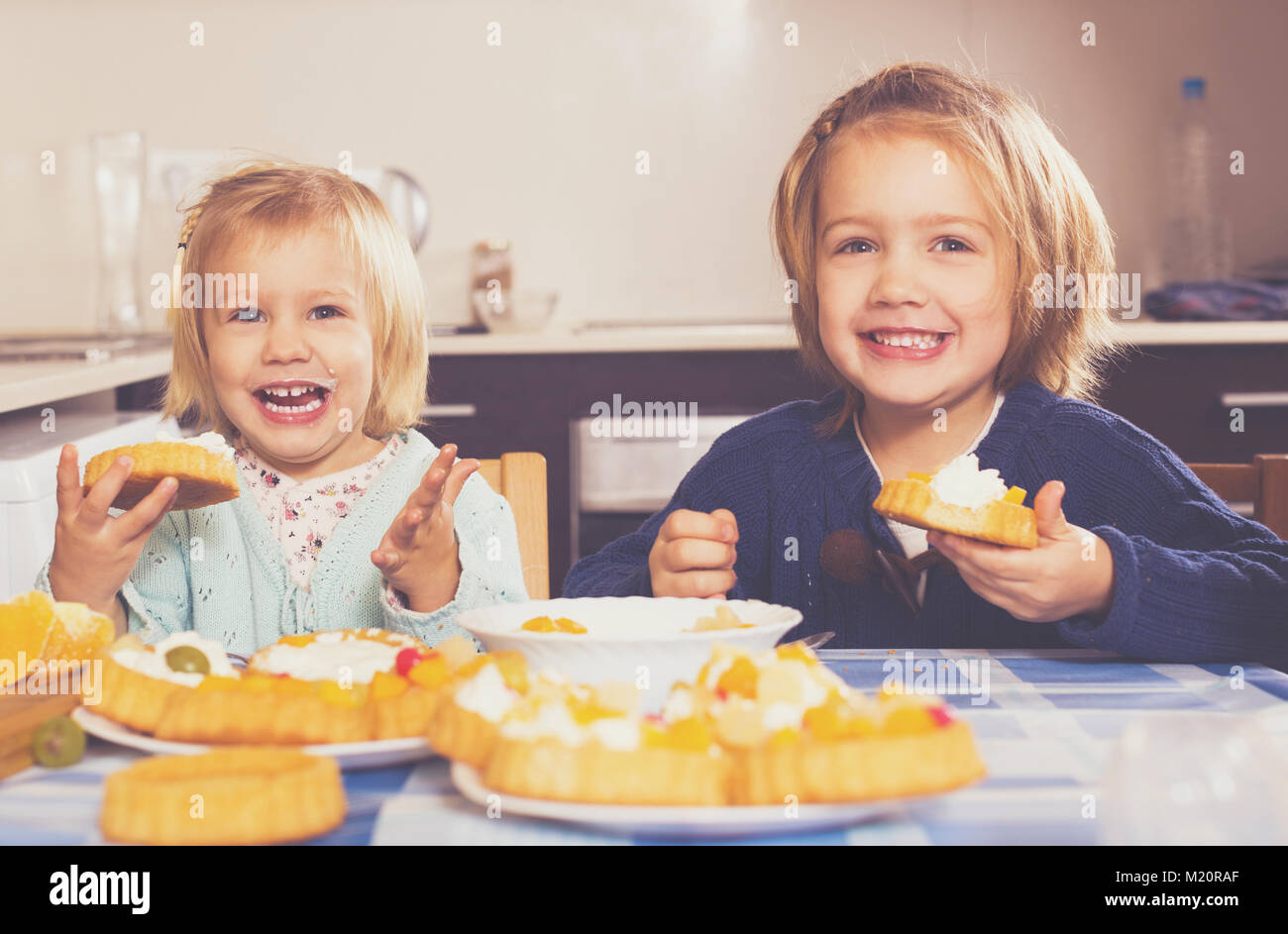 Happy girls sitting at table and eatin festive cakes Stock Photo - Alamy