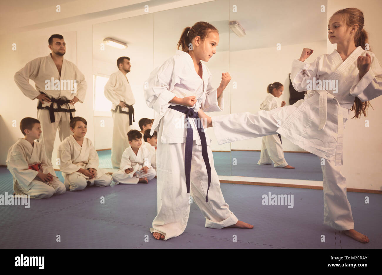 Cheerful positive pair of little girls practicing new karate moves ...