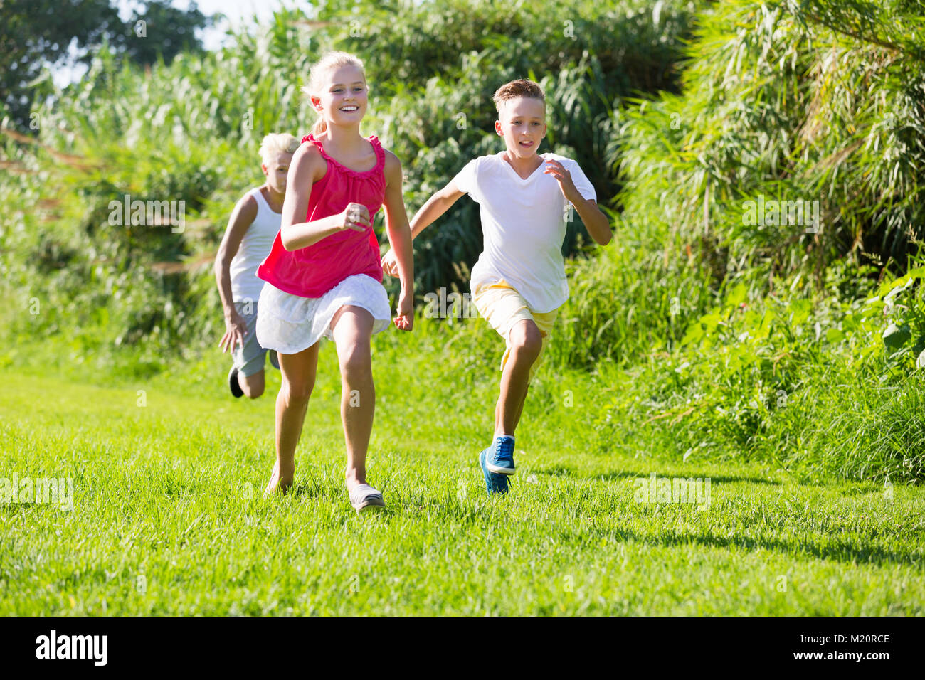 positive adult kids playing active games in summer park chasing each ...