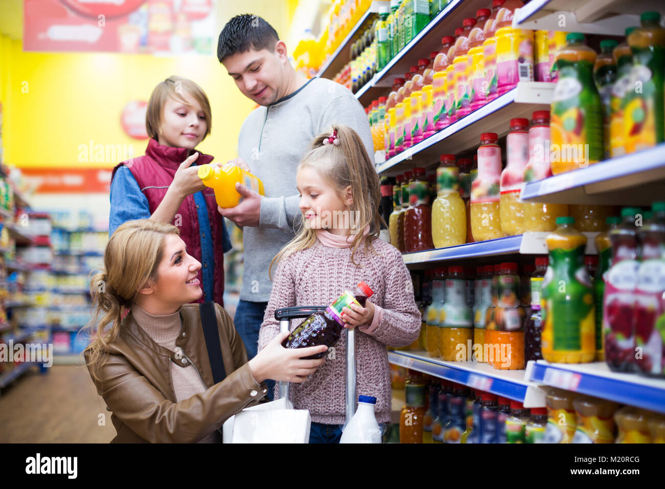 Positive young family of customers with children purchasing carbonated ...