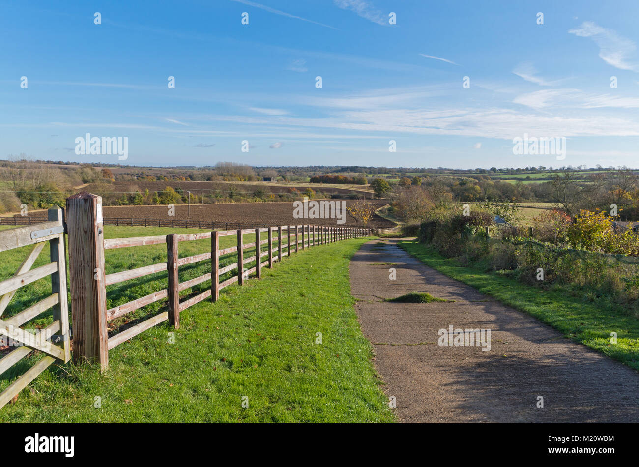 Single track lane, with a fence to the left, running downhill from the ...