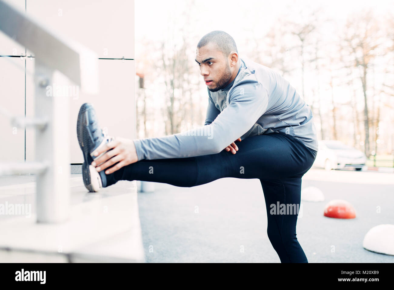 Male athlete doing stretching exercise before run. Jogger on morning ...