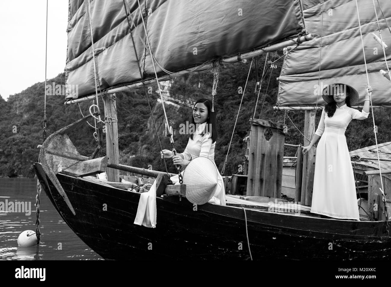 Two young Vietnamese women posing on board a sampan, a traditional ...