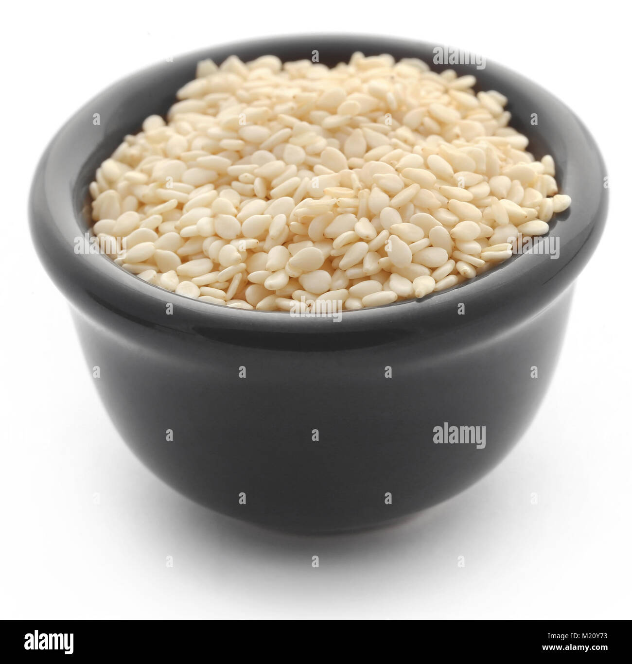 Peeled sesame seeds in a black bowl over white background Stock Photo ...