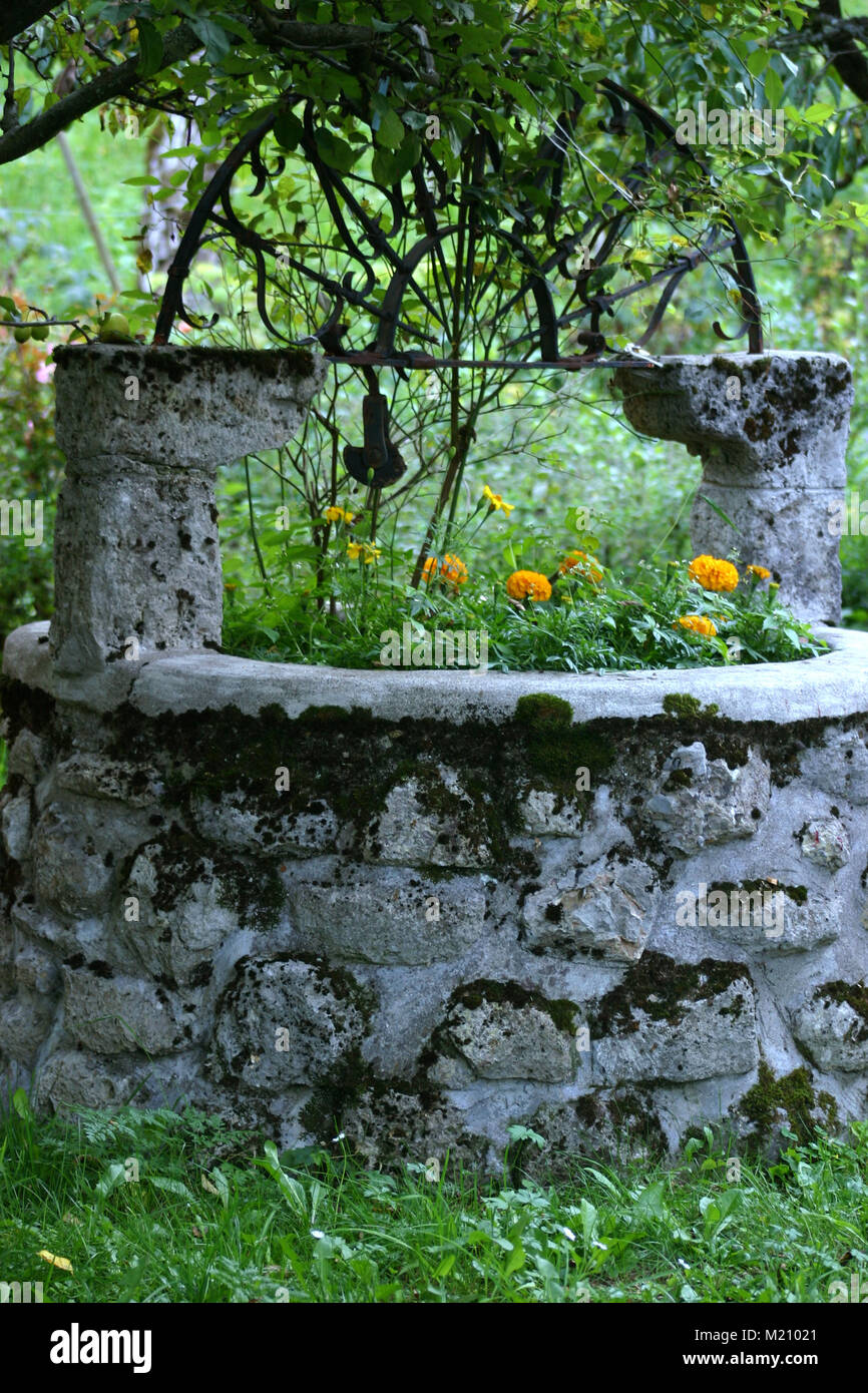 Old stone well, repurposed as a flower planter Stock Photo - Alamy