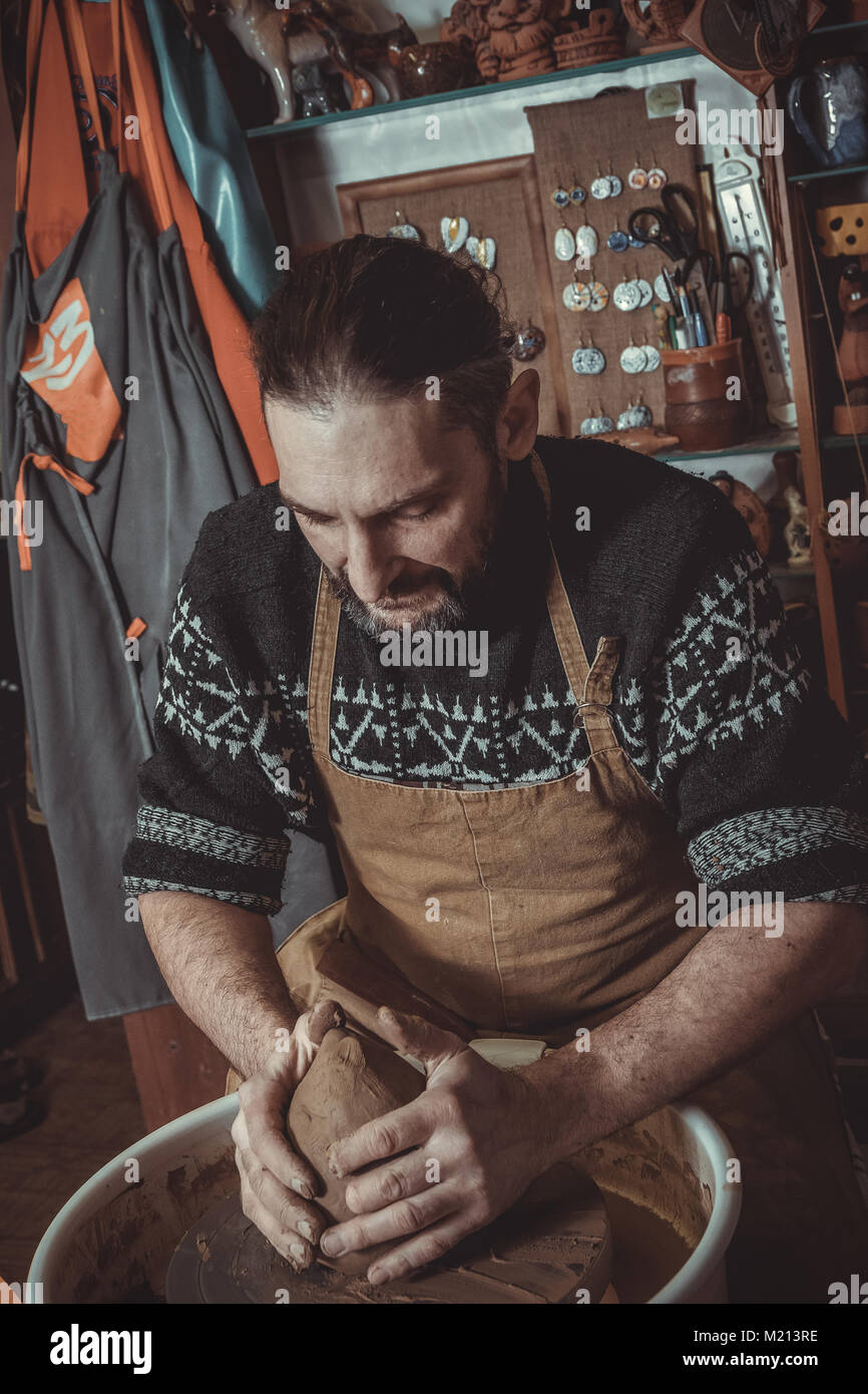 Adult male potter master mashing the clay Stock Photo - Alamy