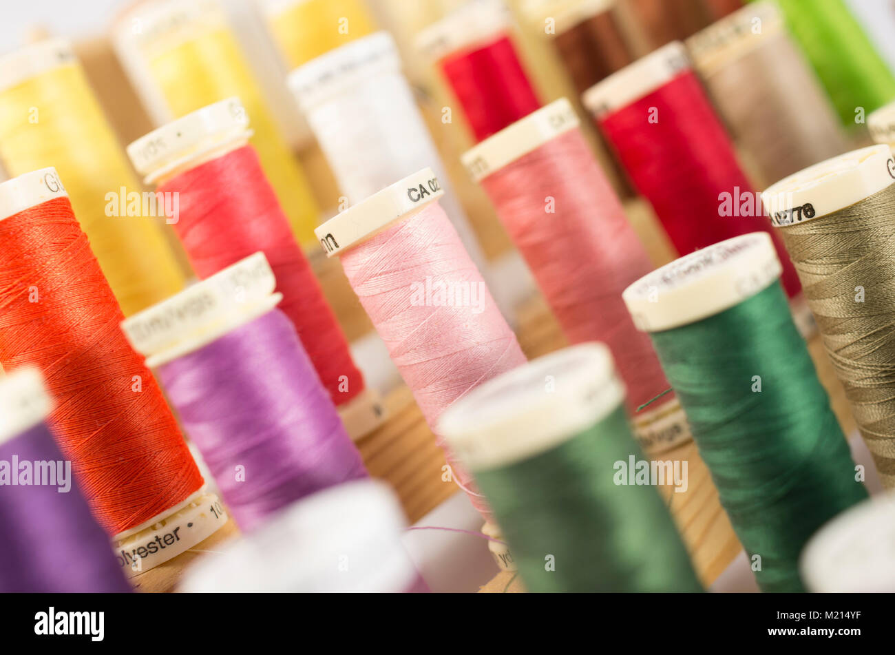 Plastic spools of thread of a variety of colors tilted at an angle and ...