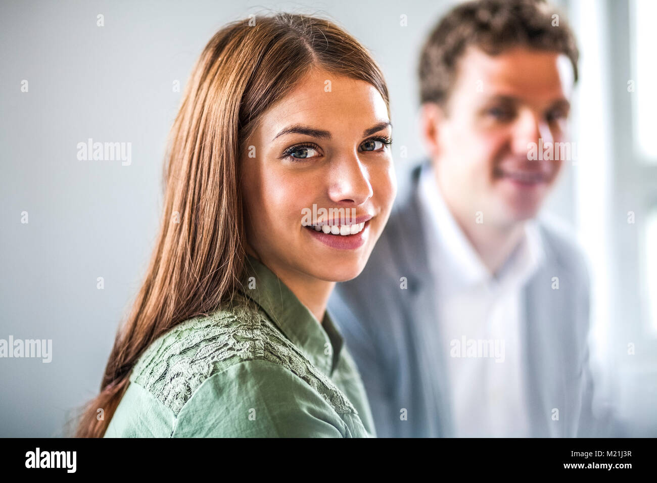 Portrait of beautiful businesswoman with male colleague in background ...