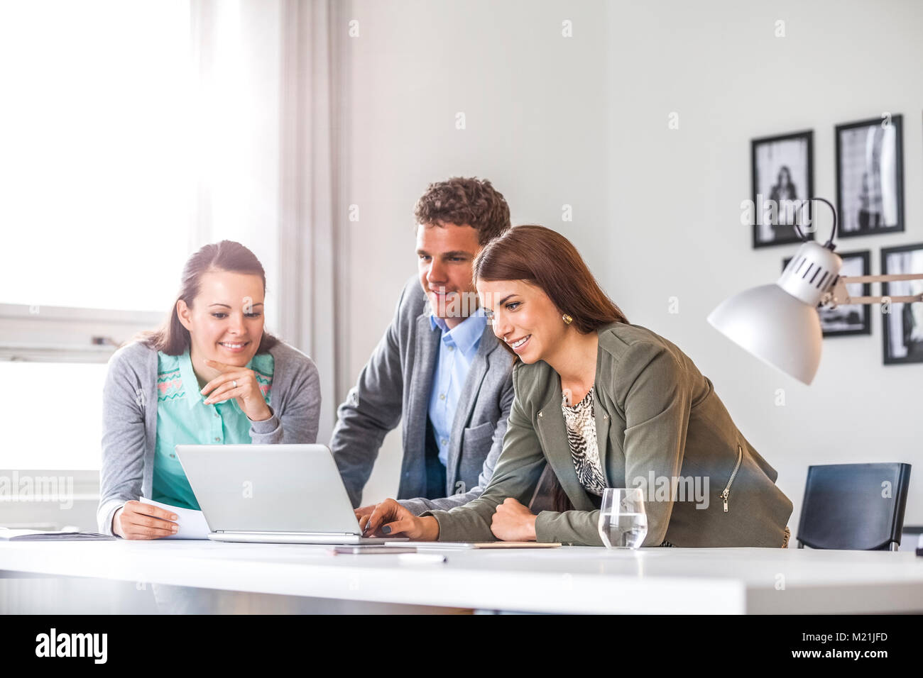 Happy young business people using laptop in office Stock Photo - Alamy