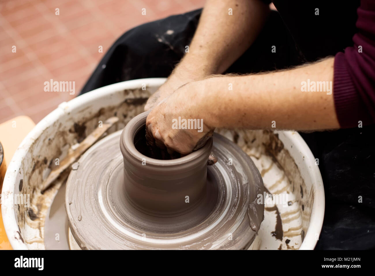 Close up detail view at an artist makes clay pottery on a spin wheel ...