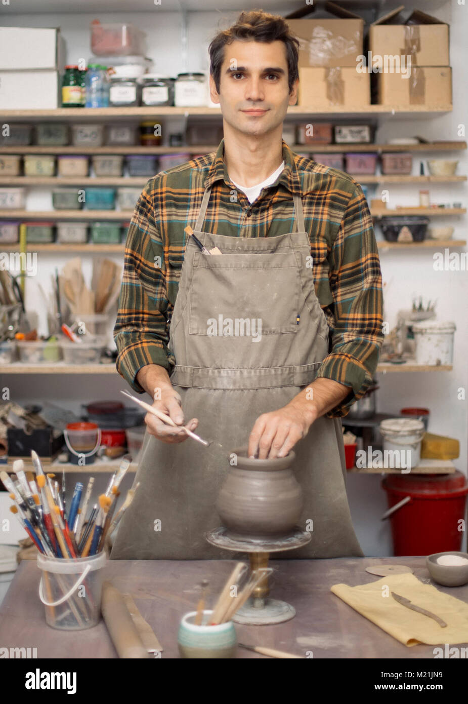 Young man making and decorating pottery in workshop Stock Photo - Alamy
