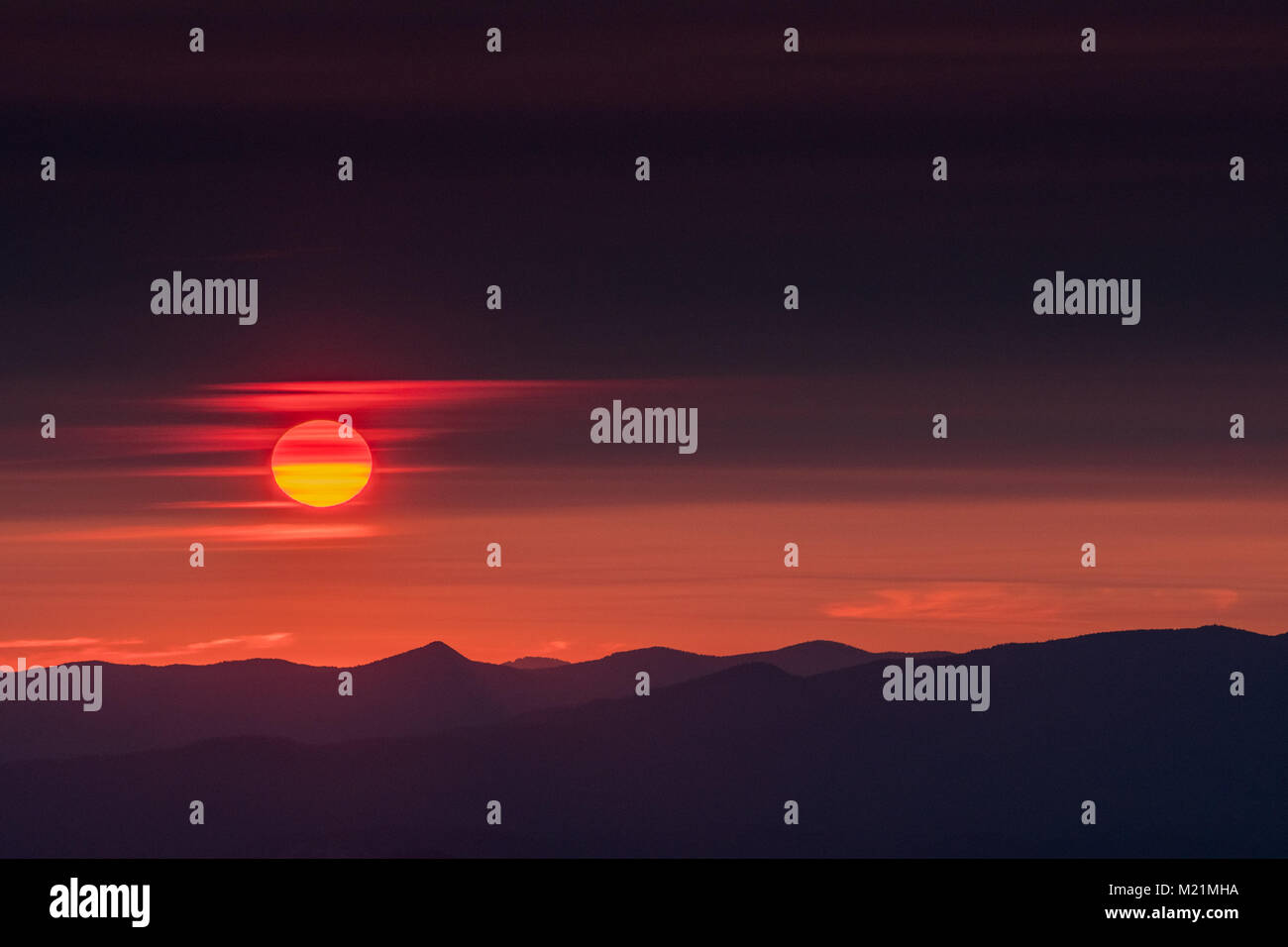 Sun Slips Through Wispy Clouds over mountain range Stock Photo - Alamy