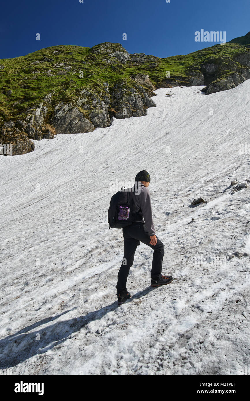 Young man hiking on a trail covered with snow in the mountains Stock ...