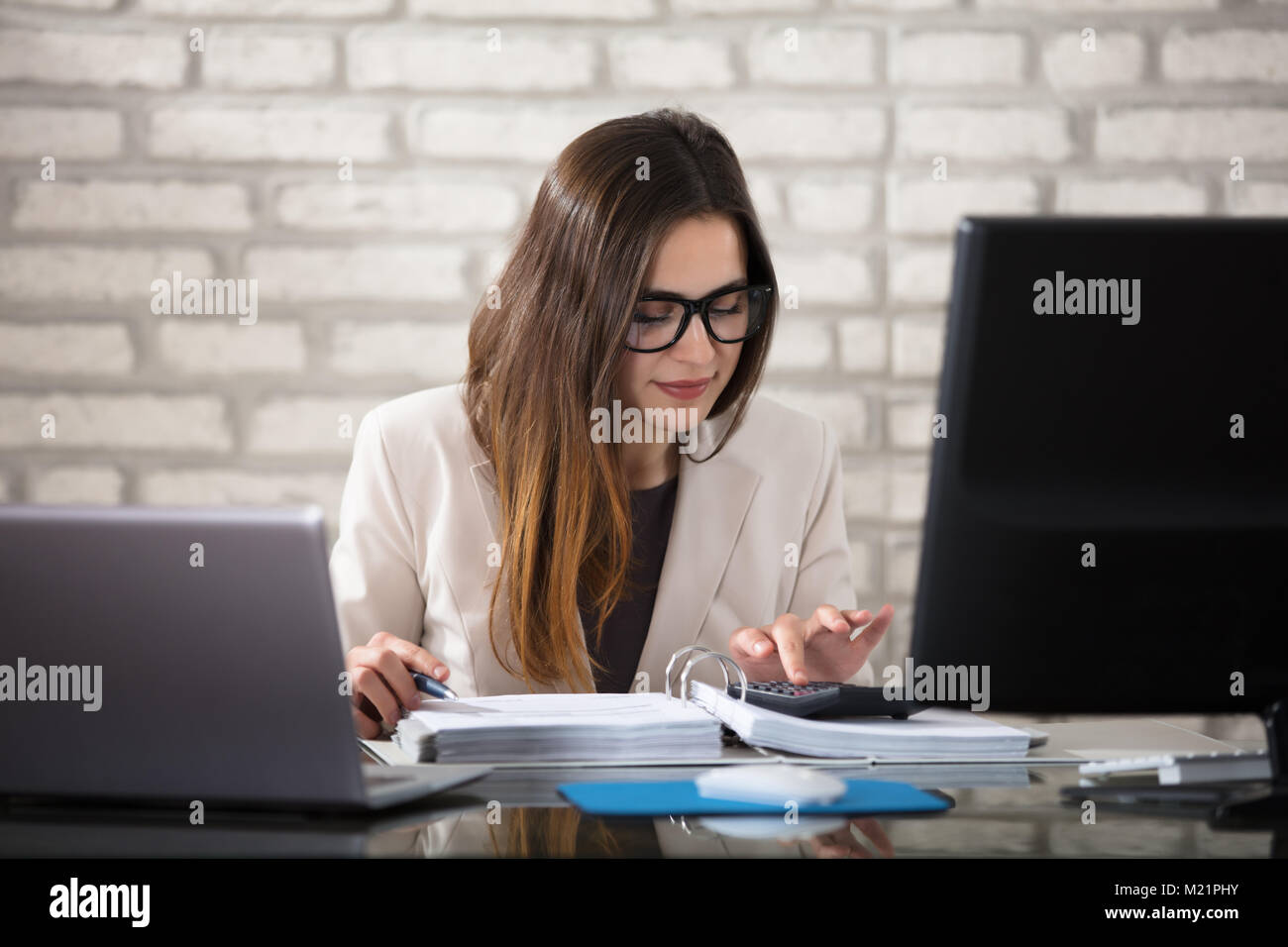 A Young Smiling Accountant Calculating Invoice Using Calculator In ...