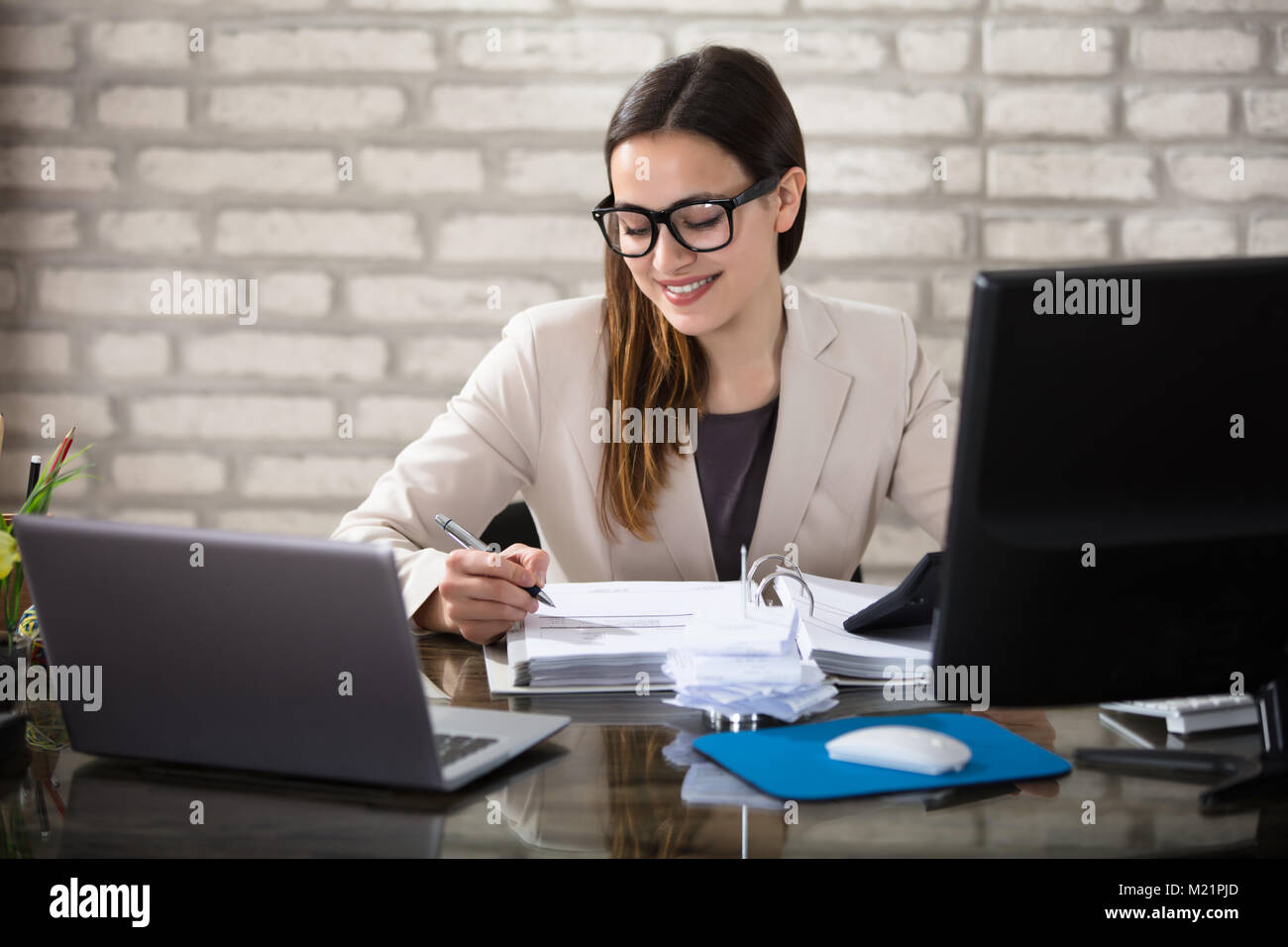 A Young Smiling Accountant Calculating Invoice Using Calculator In ...