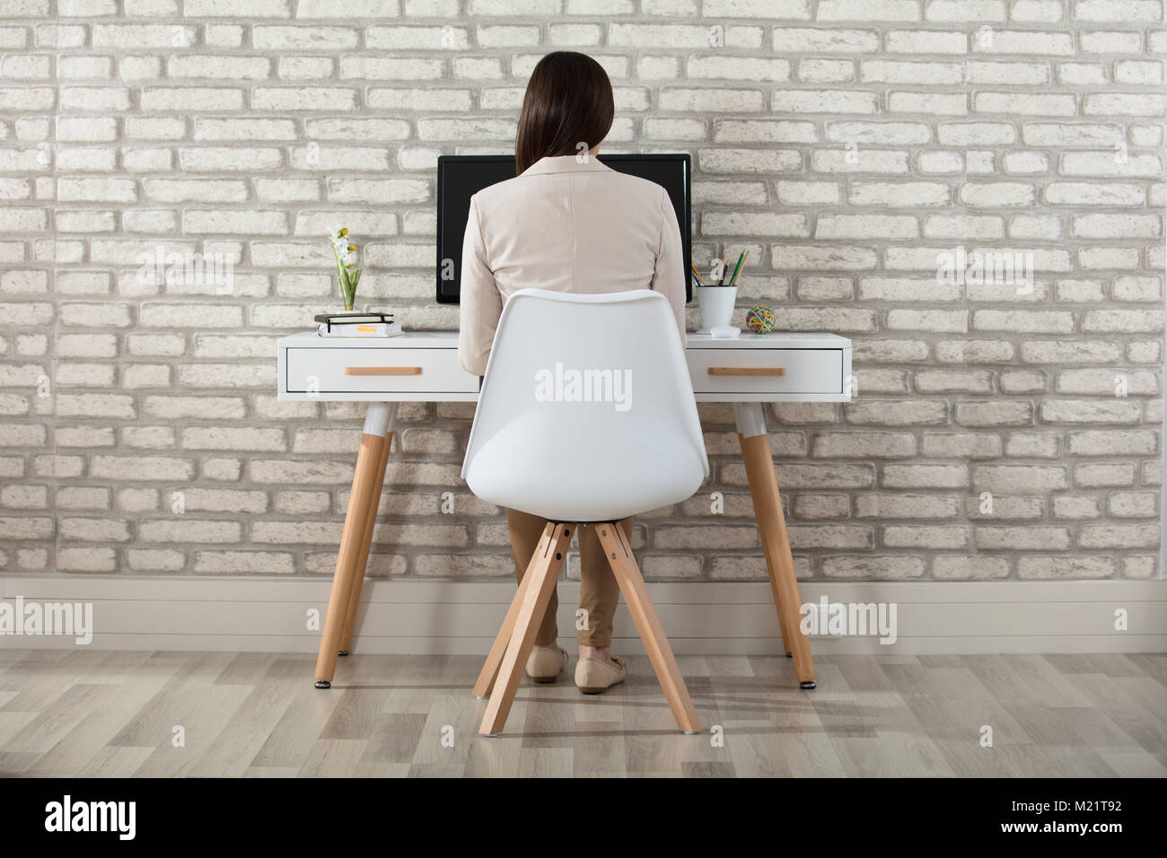 Rear View Of A Businesswoman Sitting In Front Of Computer At Workplace ...