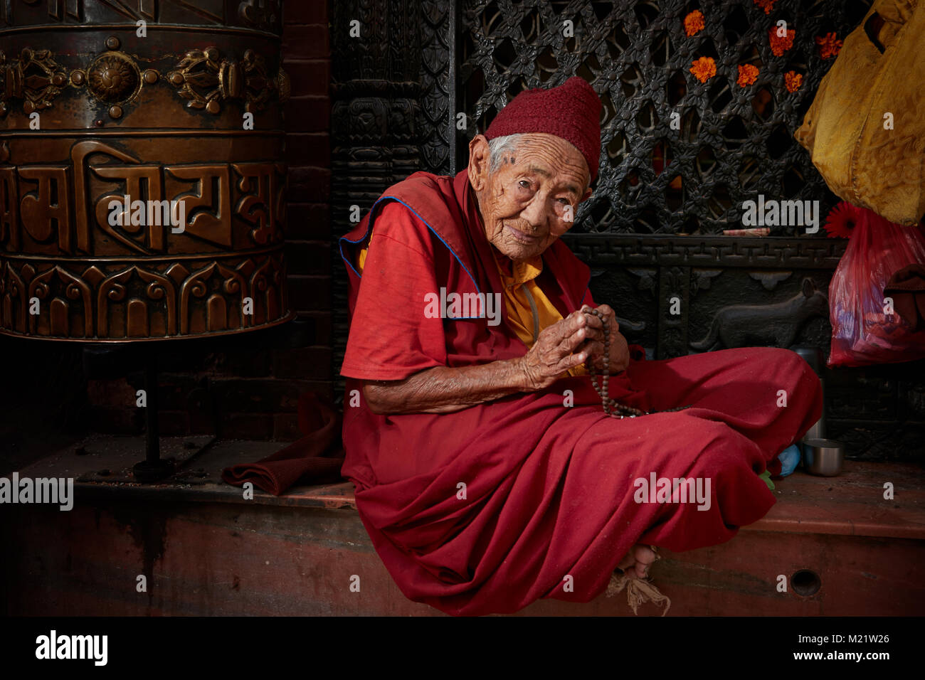Elderly female monk wearing red robe sitting and wishing Namaste to ...
