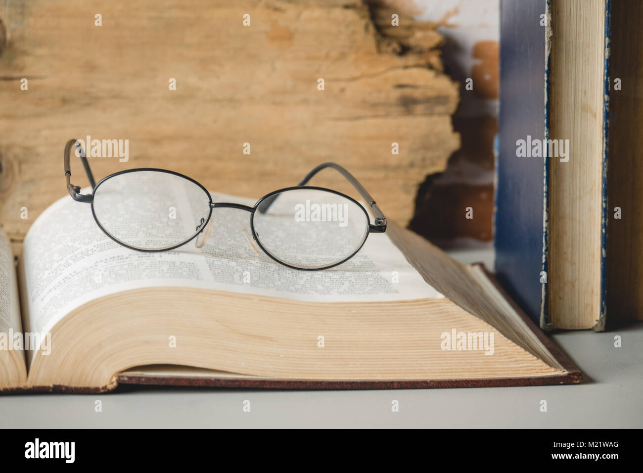 Closeup of reading glasses with open book on table Stock Photo - Alamy