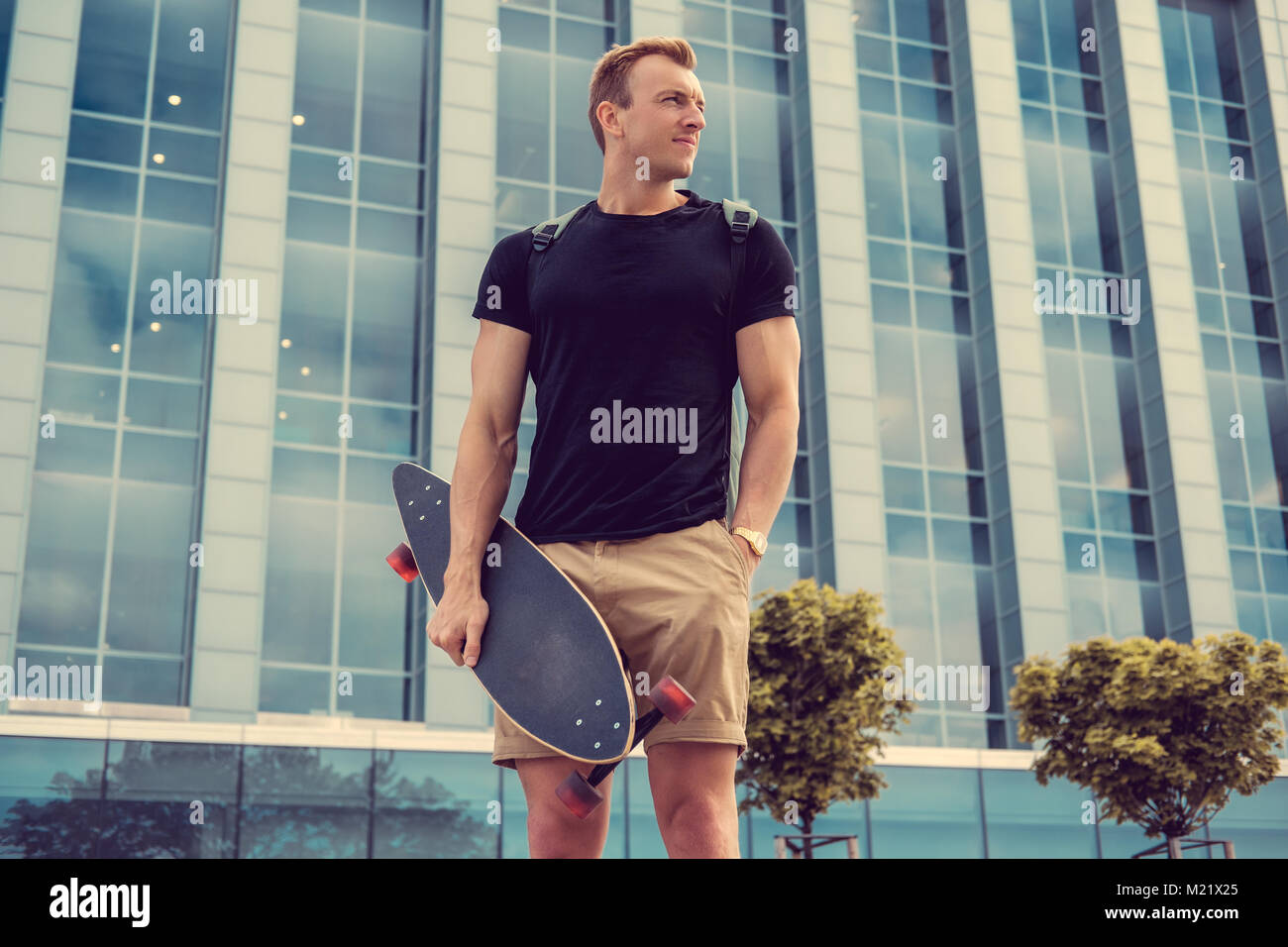 Casual urban male holding longboard Stock Photo - Alamy