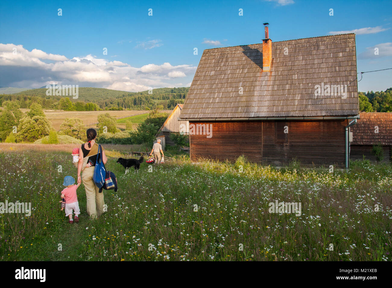 Happy rural family going home to a small house in the mountain with ble ...