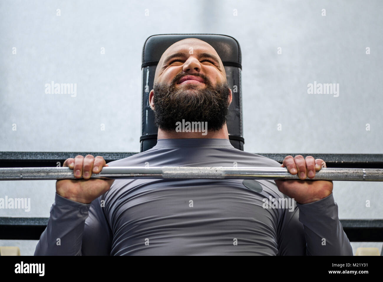 Male professional athlete pressing barbell, working hard before ...