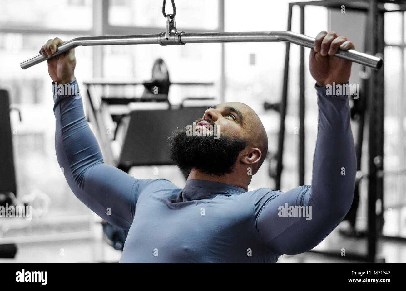Young man working hard in gym to achieve success in sports, pulldown ...