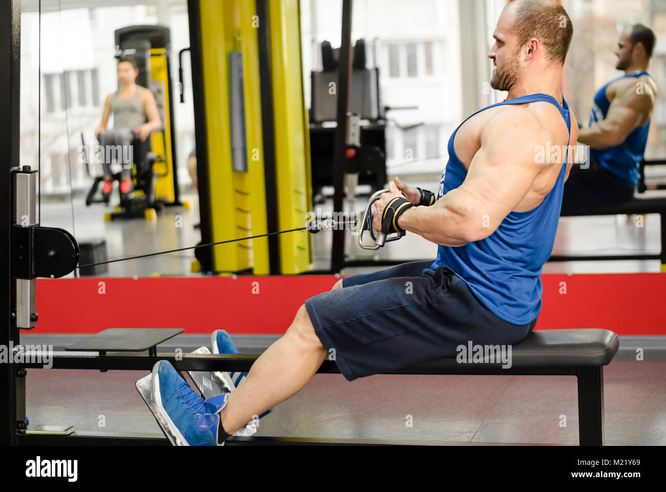 Successful male athlete doing seated cable rows, strong man training in ...