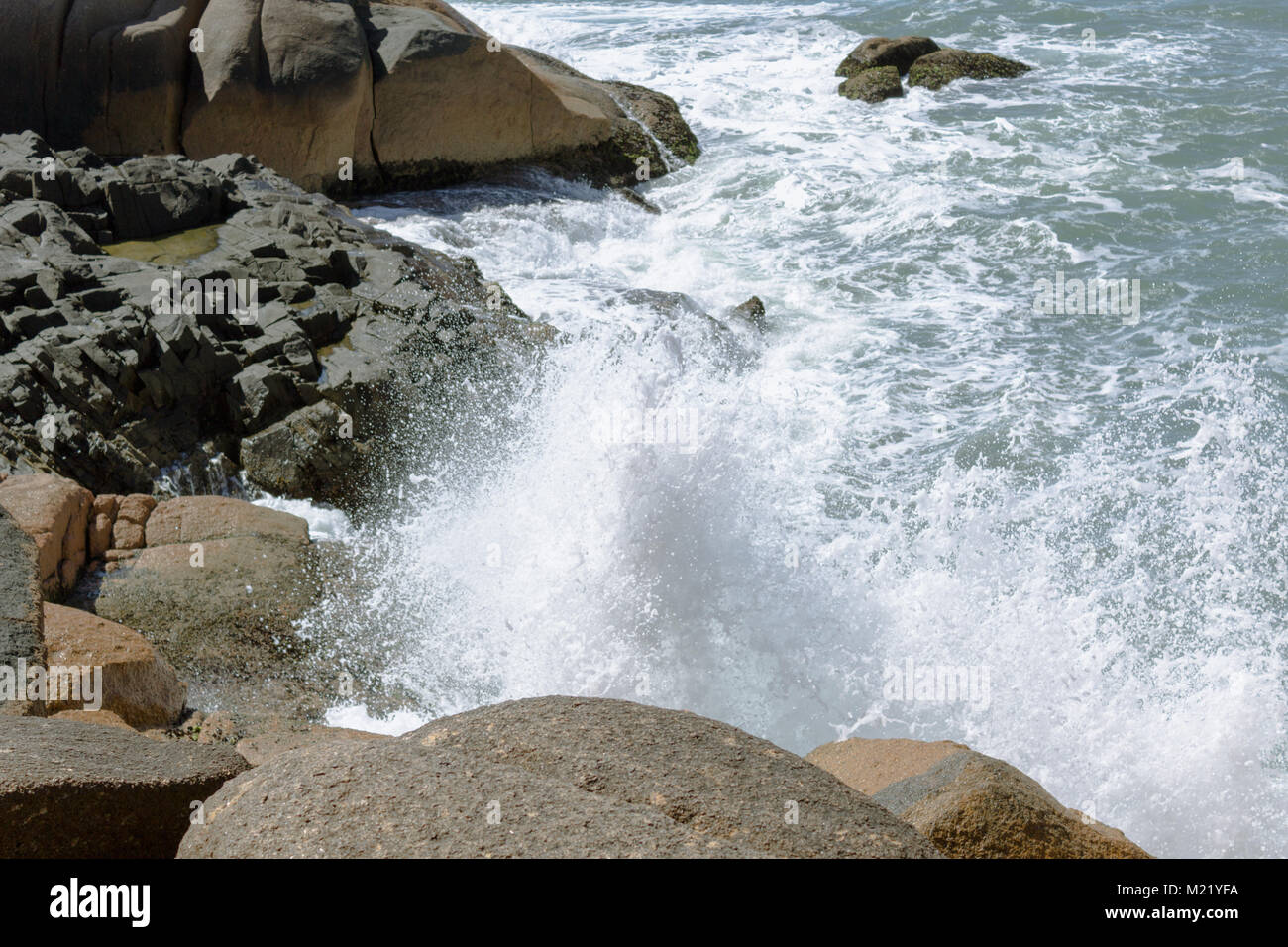 Waves crash against rock in a sunny day Stock Photo - Alamy