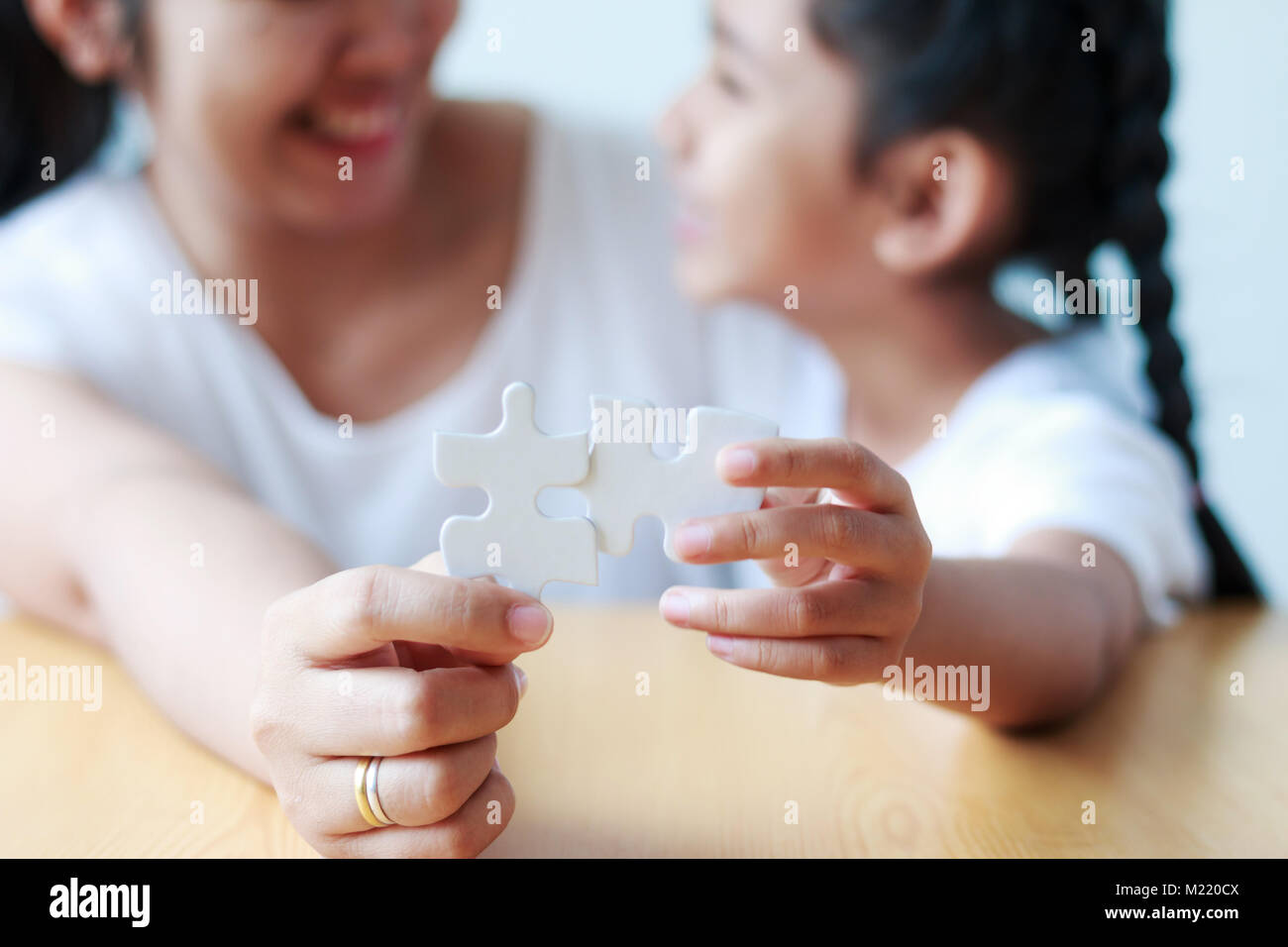 Asian little girl playing jigsaw puzzle with her mother for family ...