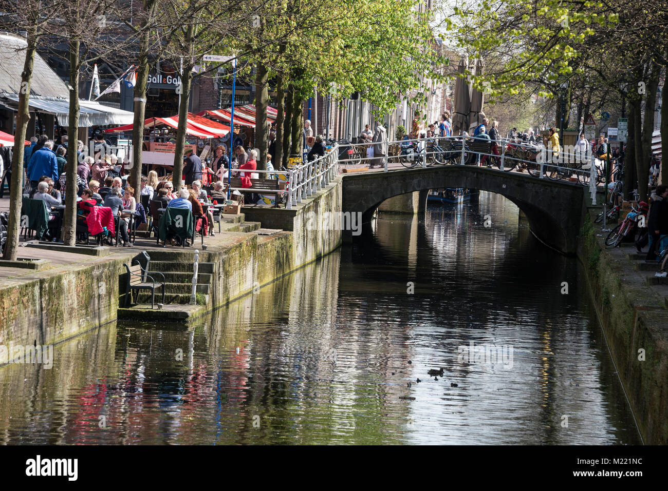 Outdoor restaurants line the banks of the Delftse Schie waterway or ...