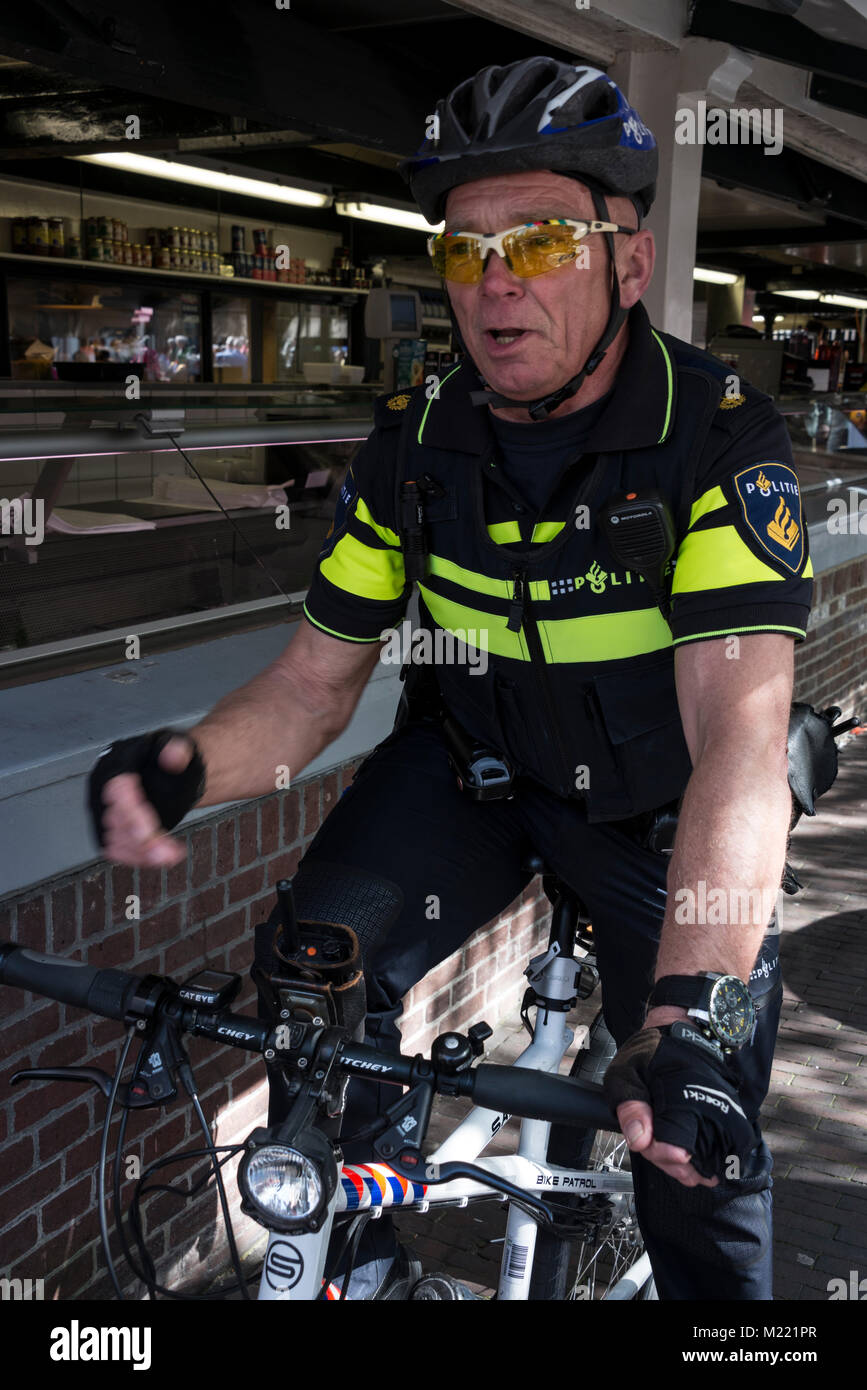 A Delft City policeman on his patrol wearing his required cycle helmet ...
