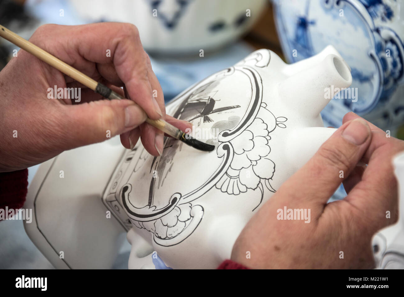 A skilled freehand artist painting a vase in the atelier at the world’s ...
