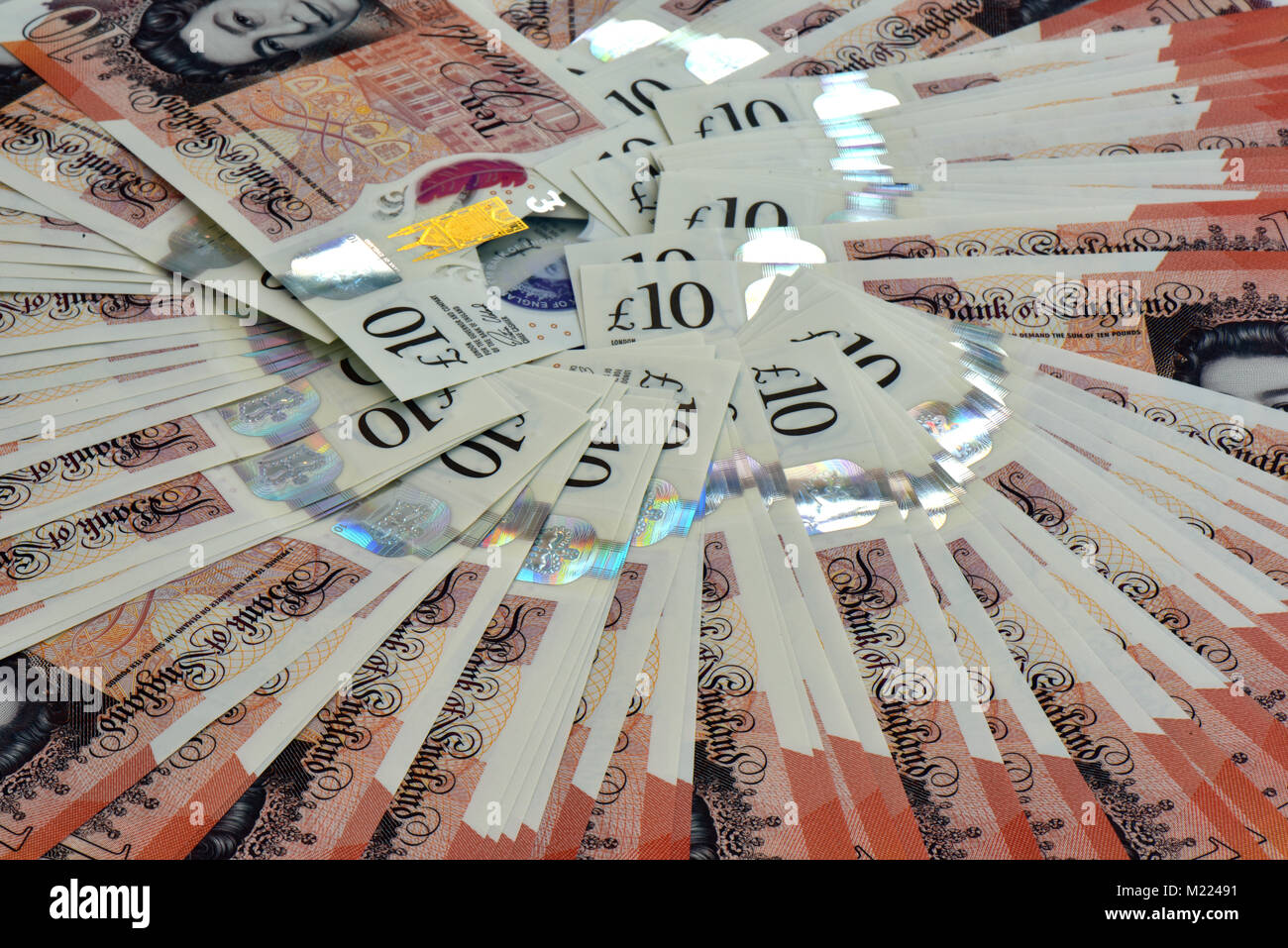 A lot of money in cash and ten pound notes on a table fanned out in a ...