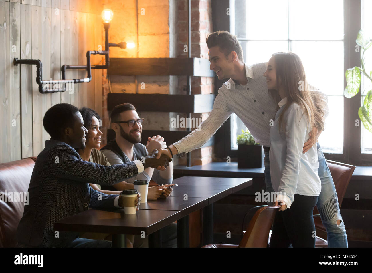Happy couple getting acquainted with multiracial people coming a Stock ...