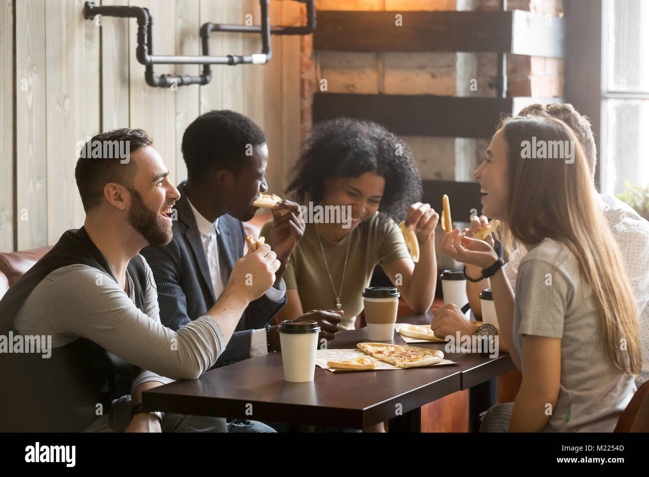 Multiracial happy young people laughing eating pizza together in Stock ...