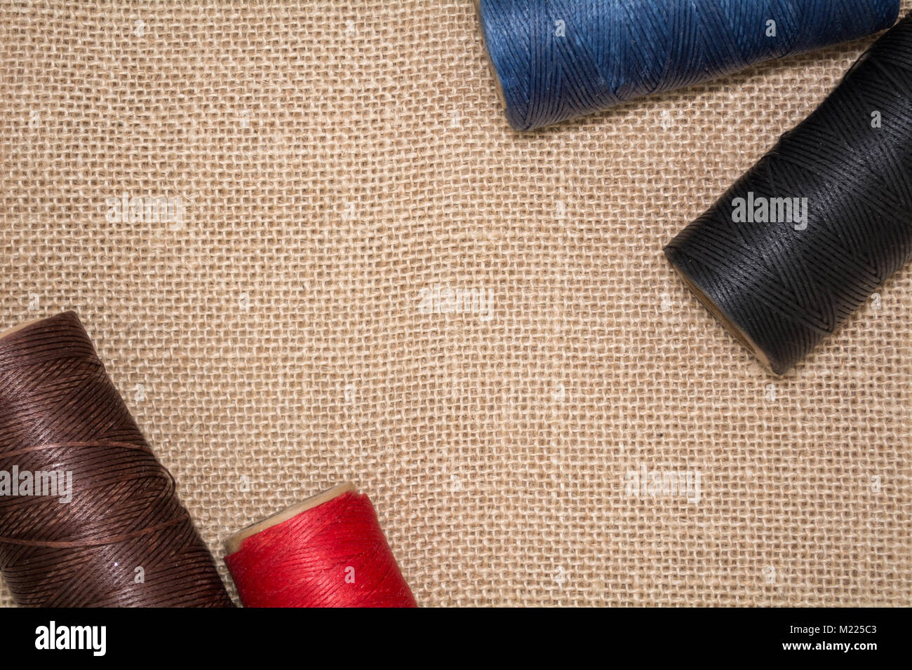 Four coils of threads on a linen background. Red, blue, brown and black ...