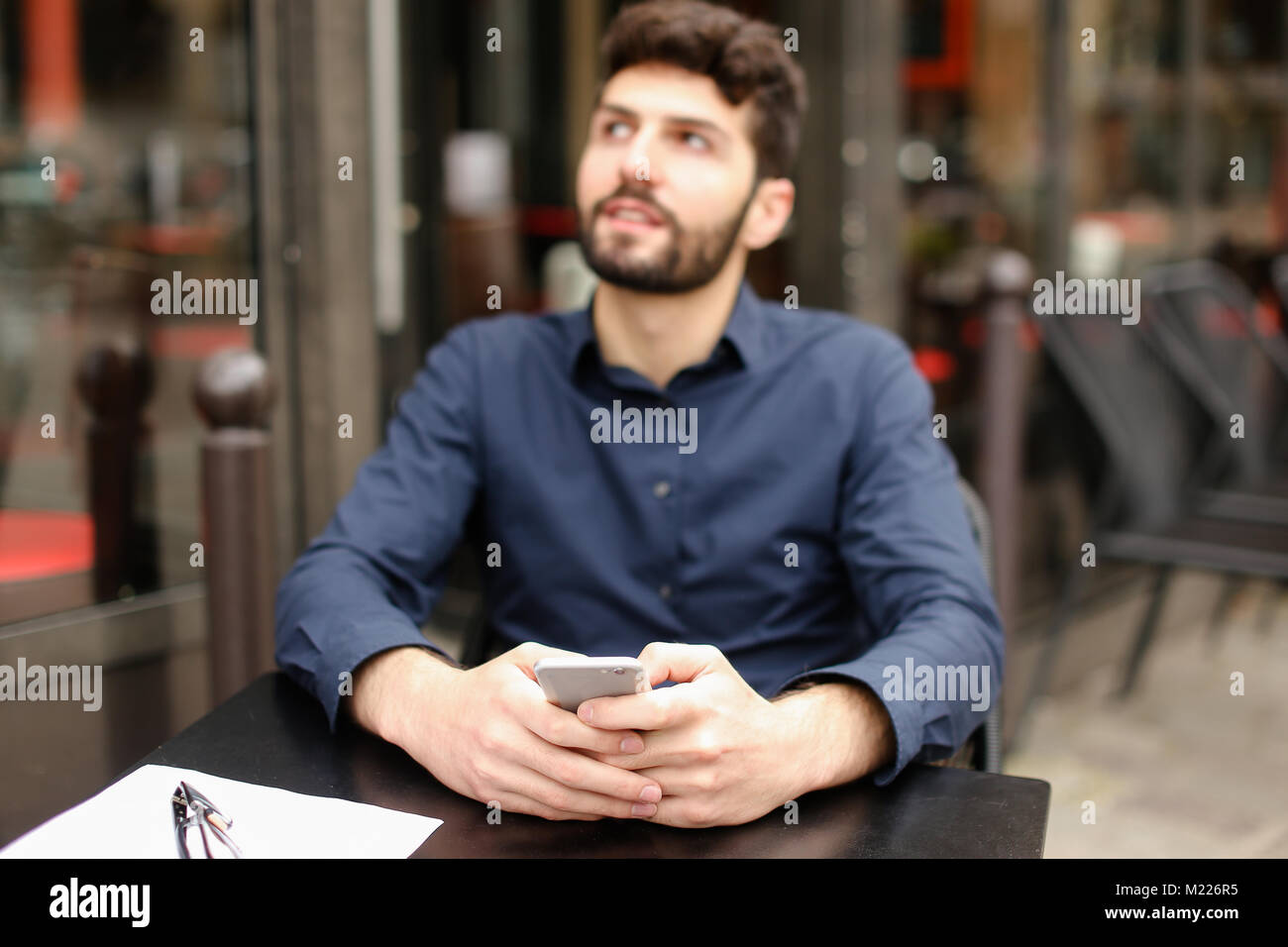 Happy man sitting at cafe table and chatting by smartphone with Stock ...