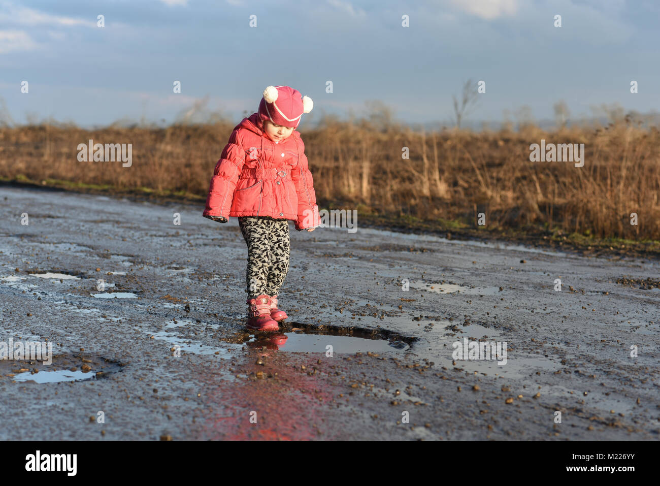 Concept - happy childhood. Little girl plays in puddle, children's fun ...