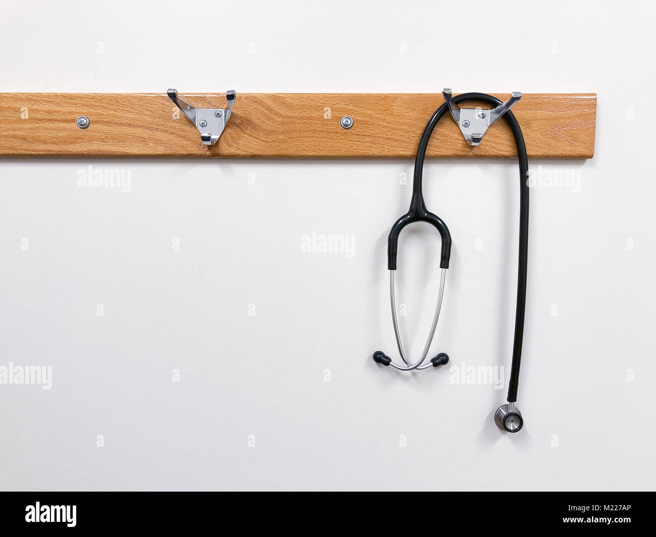 A Stethoscope hangs from a coat rack in a hospital room. minimal color ...