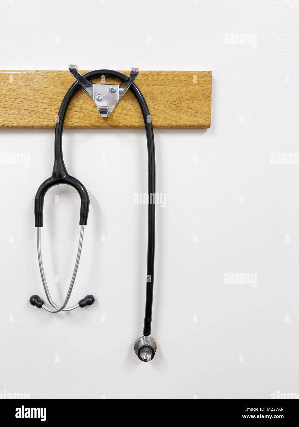 A Stethoscope hangs from a coat rack in a hospital room. minimal color ...