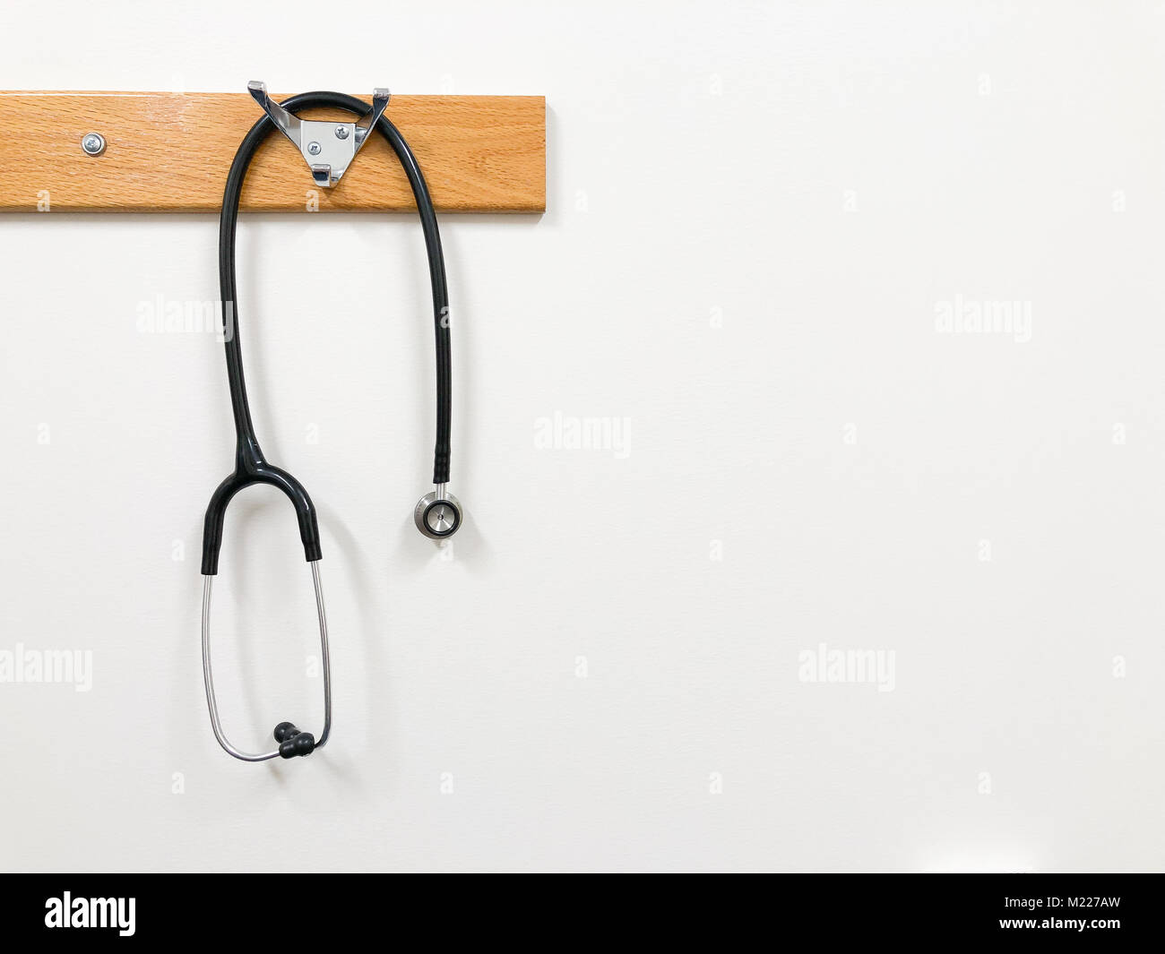A Stethoscope hangs from a coat rack in a hospital room. minimal color ...