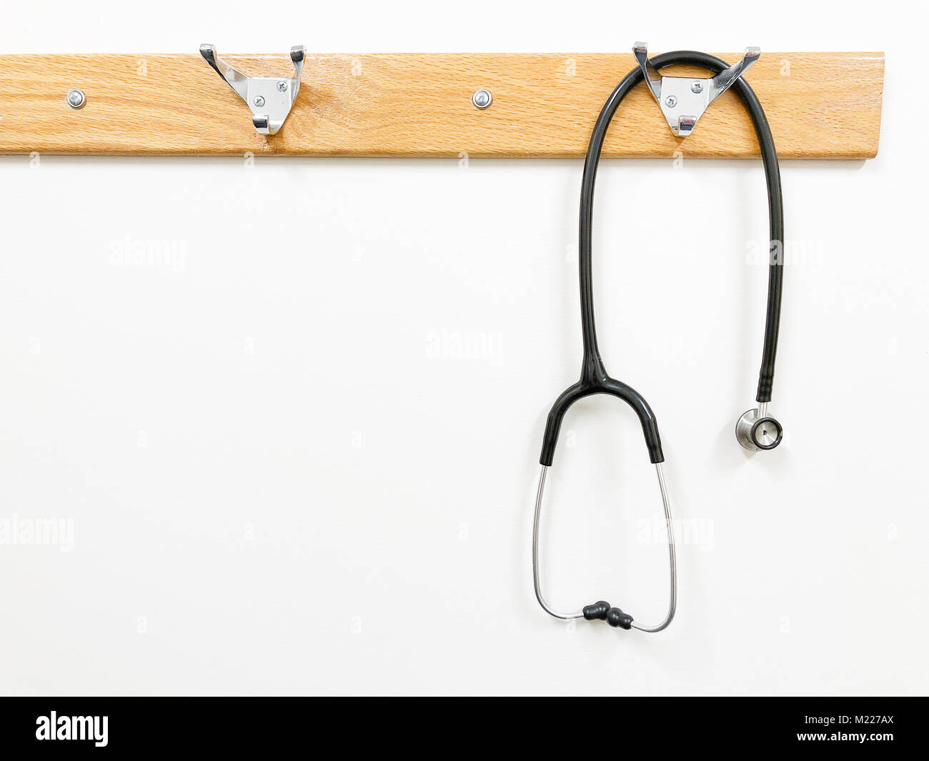 A Stethoscope hangs from a coat rack in a hospital room. minimal color ...