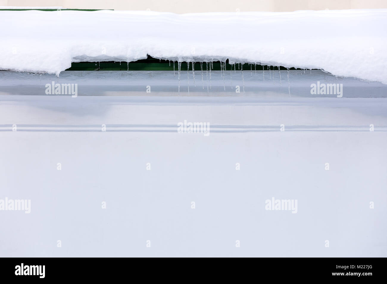 snow and icicles on the edge of the roof, white wall background Stock ...