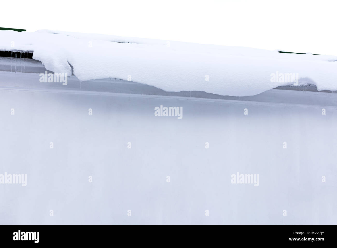snow overhanging on roof of city building with white walls Stock Photo ...