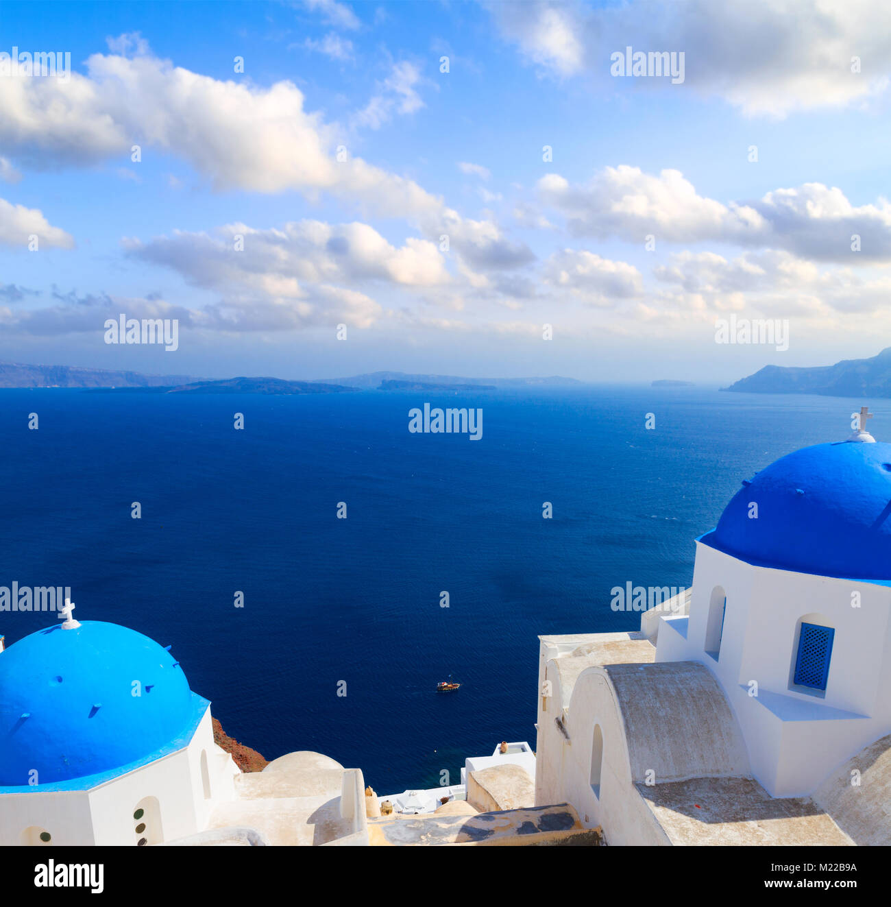 volcano caldera with classical blue church domes and Aegan blue sea and ...