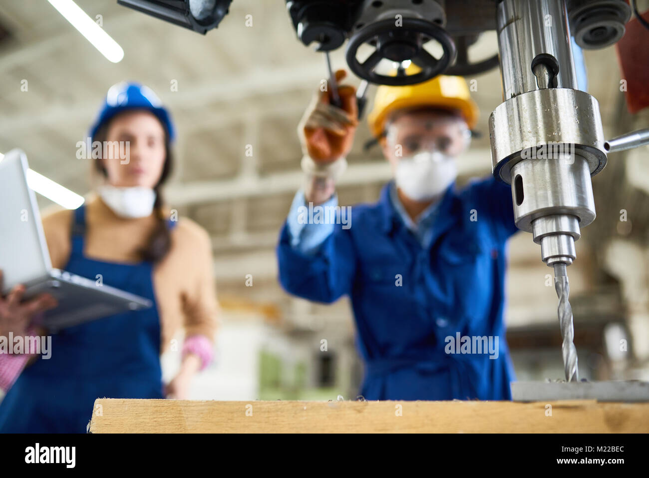 Portrait of two female factory workers operating boring mill at modern ...