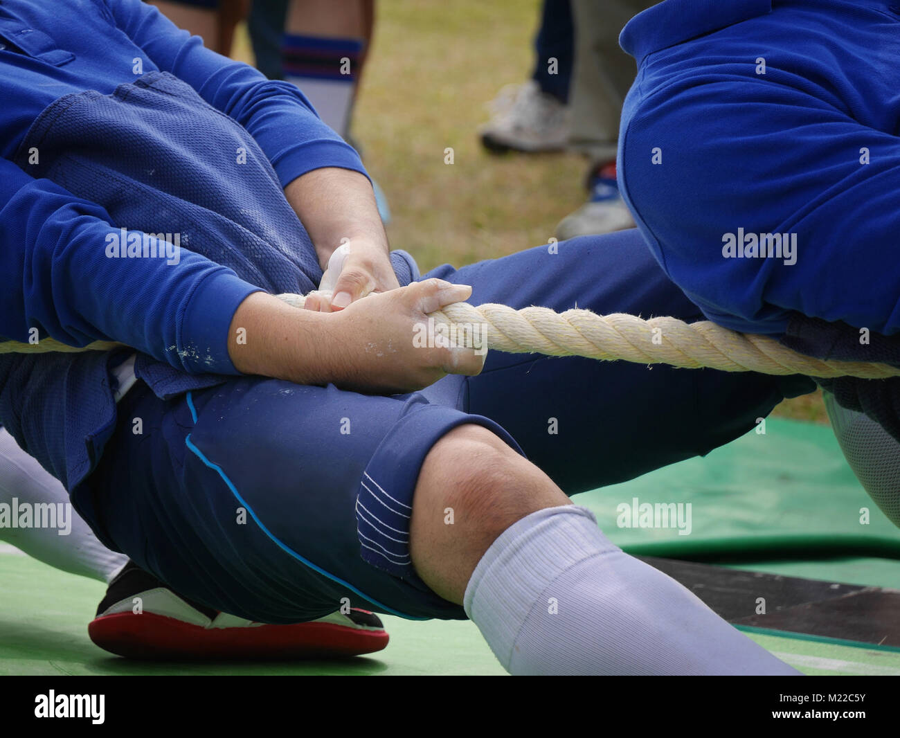 Man in blue sport outfit participating in tug of war sport. Main focus ...