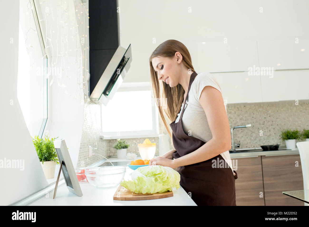 Side view portrait of pretty young woman cooking dinner in modern ...