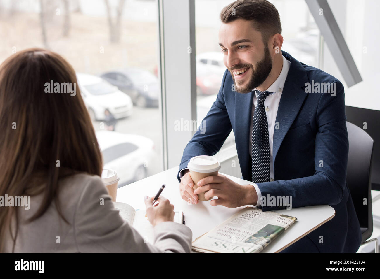 Portrait of two cheerful business people, man and woman, drinking ...
