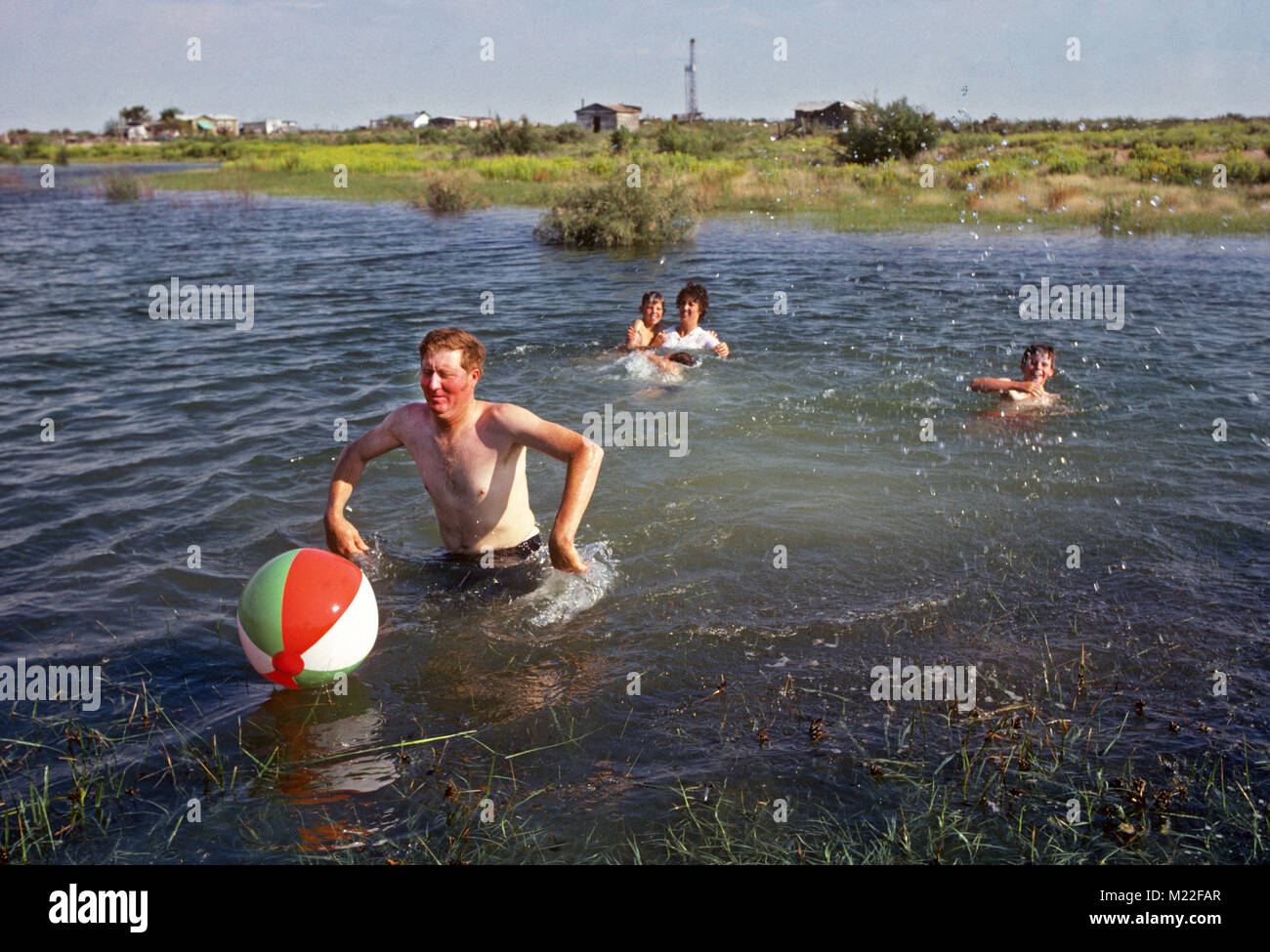 A farm family swimming in a farm pond on a hot summer day near ...